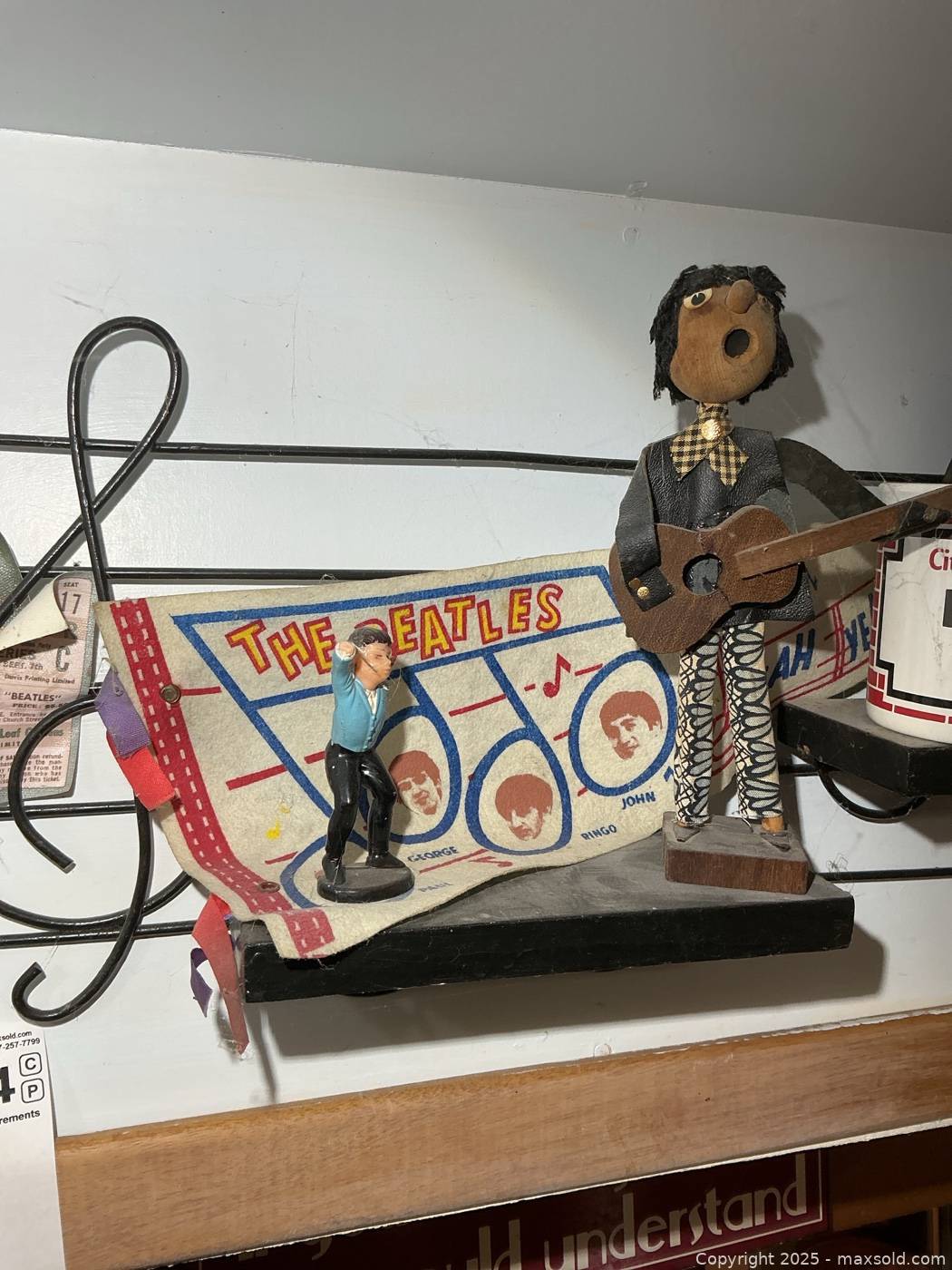 Metal music-note shelf with Beatles memorabilia and decor items | Maxsold