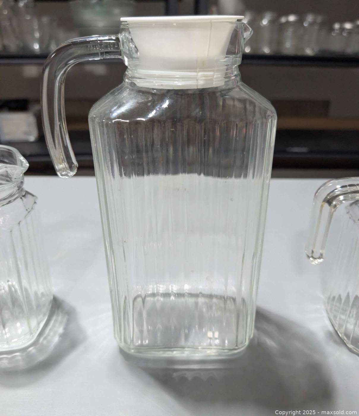 Three clear glass ribbed pitchers with lids | Maxsold